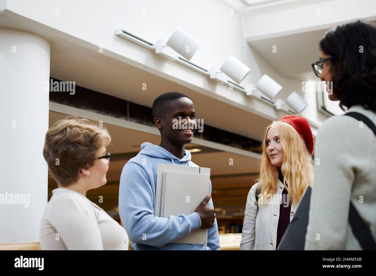 Group of students talking in library Stock Photo - Alamy