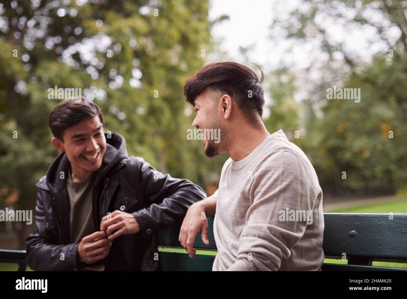 Men sitting on bench and talking Stock Photo - Alamy