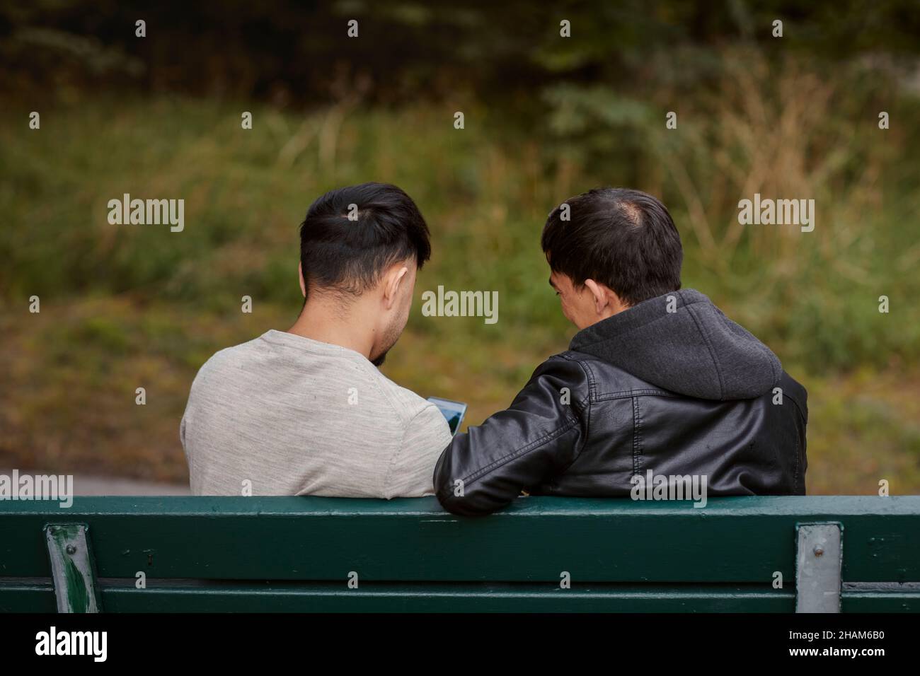 Rear view of men sitting on bench Stock Photo - Alamy