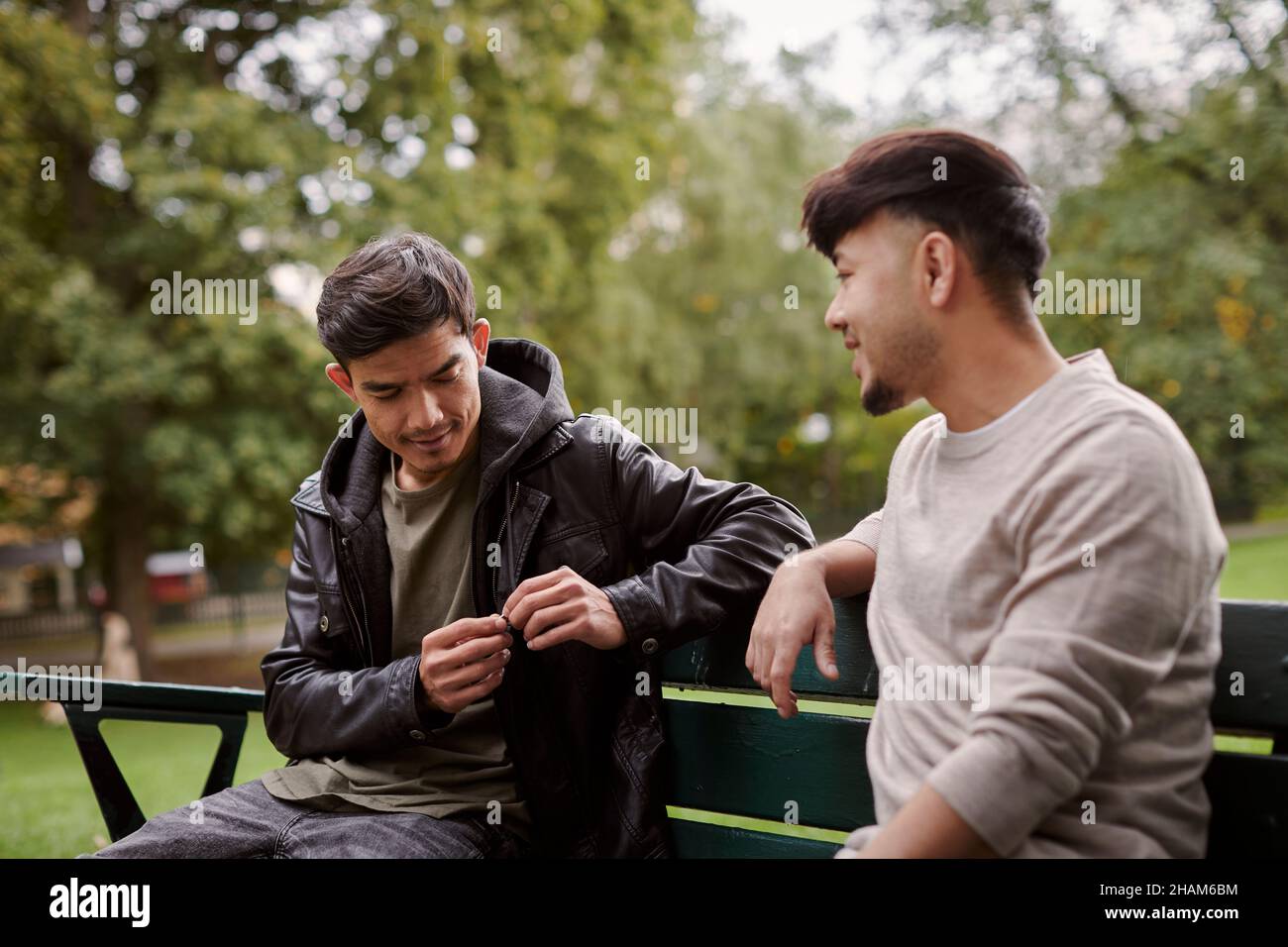 Men sitting on bench and talking Stock Photo - Alamy