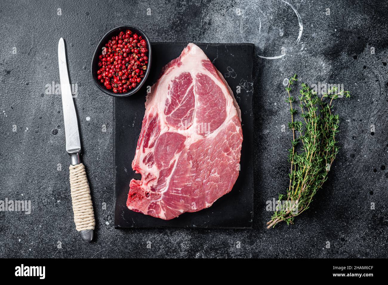 Pork neck steak from raw meat on marble board with herbs. Black ...