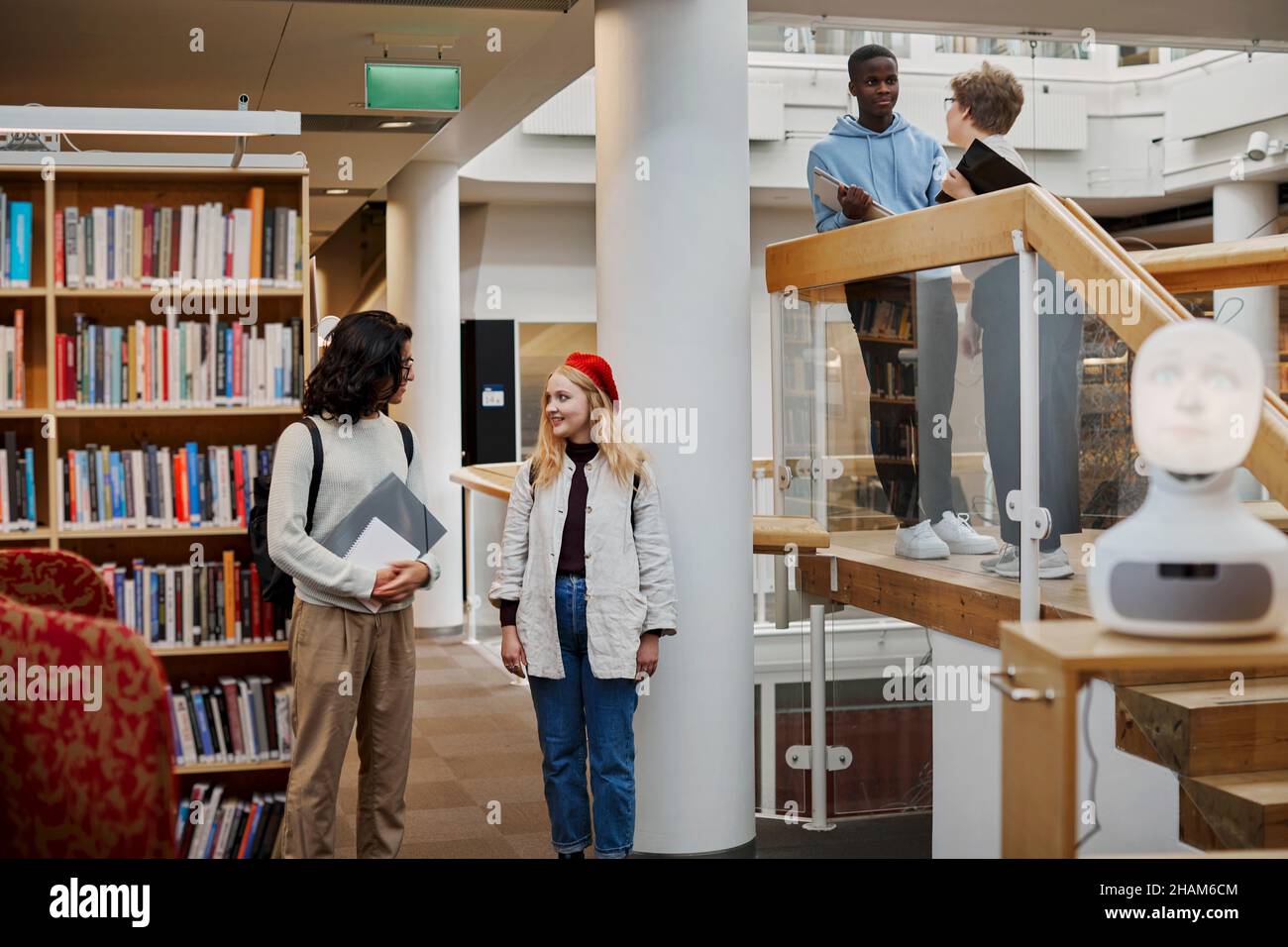 Male and female students talking in library Stock Photo - Alamy