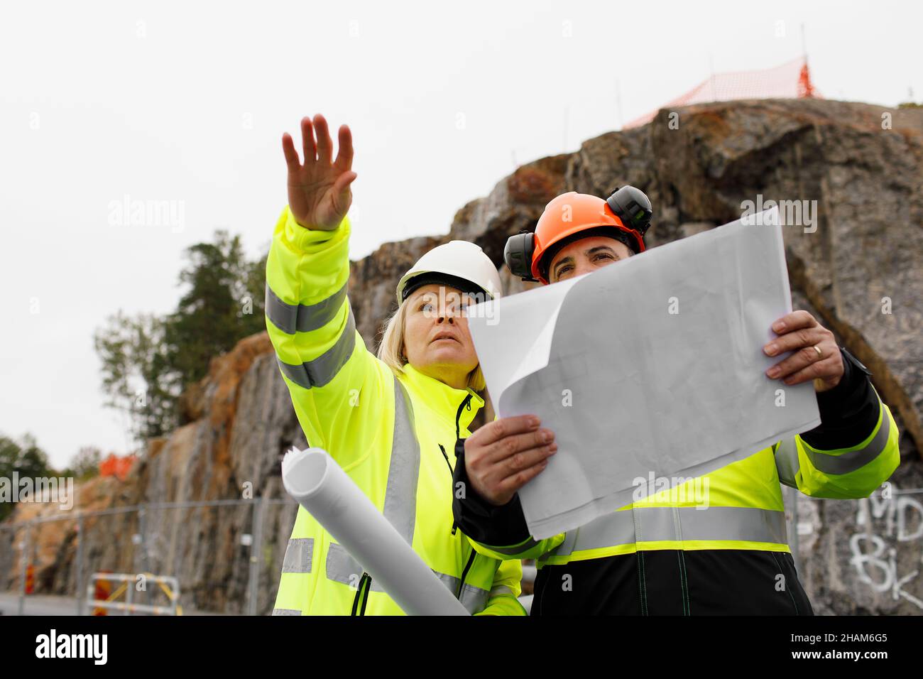 Engineers in reflecting clothing looking at blueprints Stock Photo - Alamy