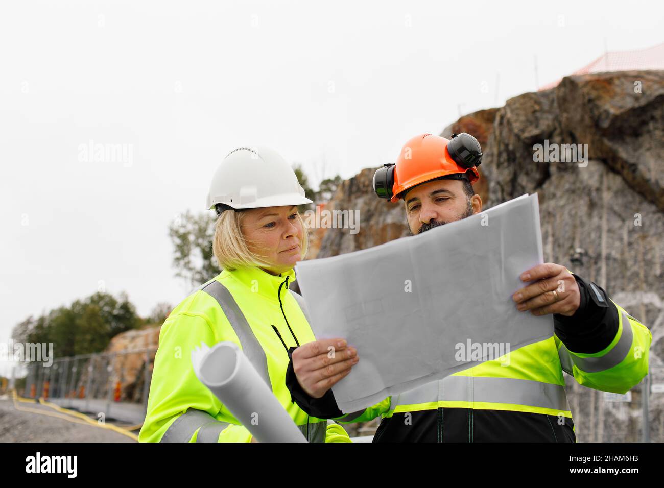 Engineers in reflecting clothing looking at blueprints Stock Photo - Alamy