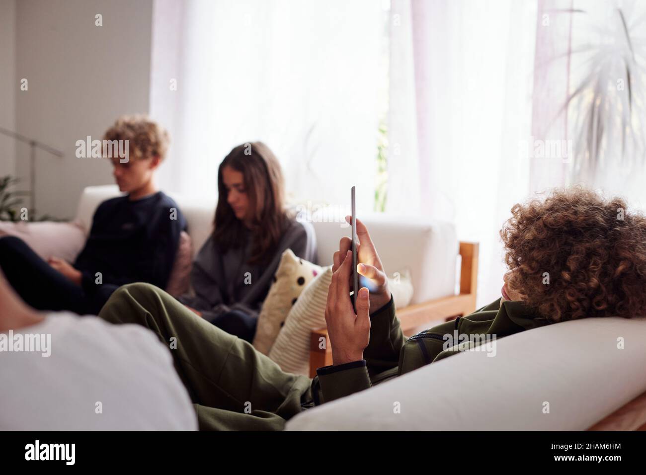 Siblings using smart phones in living room Stock Photo - Alamy