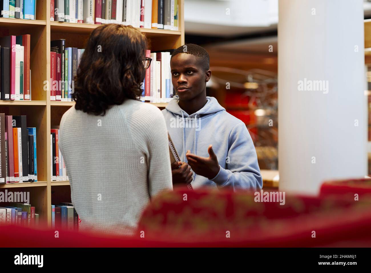 Two students talking in library Stock Photo - Alamy