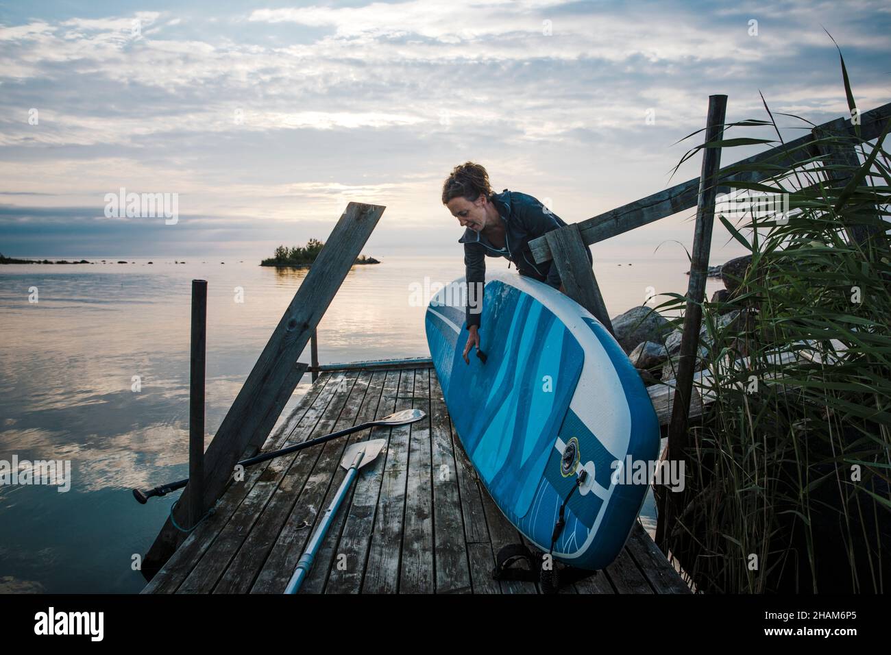 Woman carrying paddleboard at lake Stock Photo - Alamy