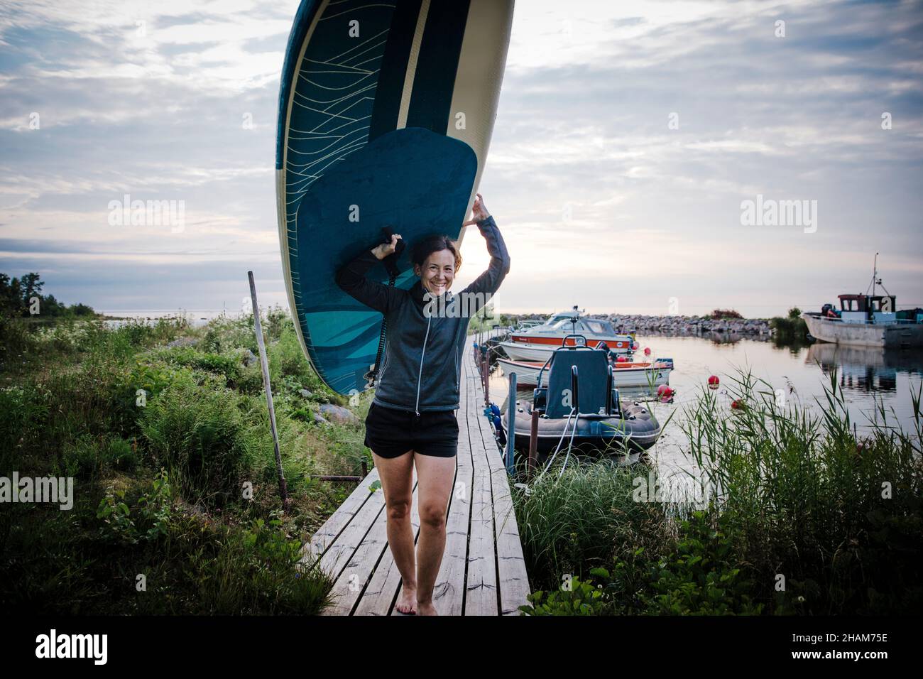 Woman carrying paddleboard at lake Stock Photo - Alamy