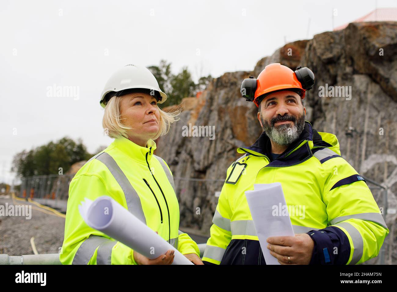 Engineers in reflecting clothing holding blueprints Stock Photo - Alamy