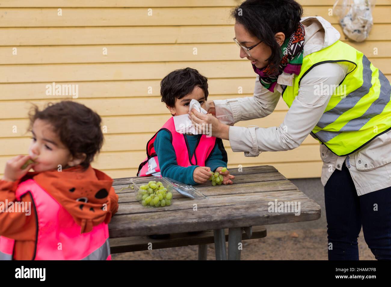 Preschool teacher and students eating grapes outdoors Stock Photo - Alamy