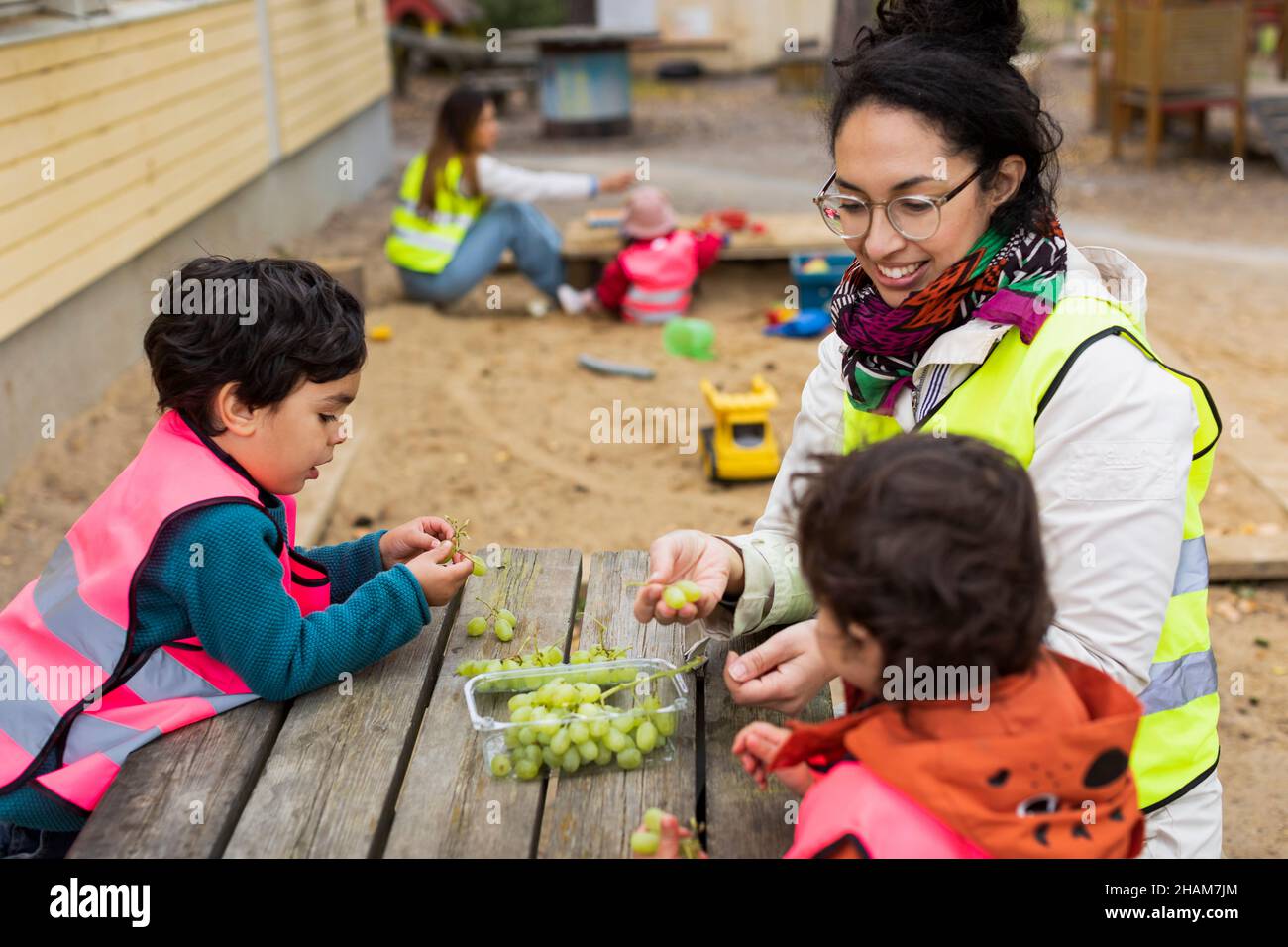 Preschool teacher and students eating grapes outdoors Stock Photo - Alamy