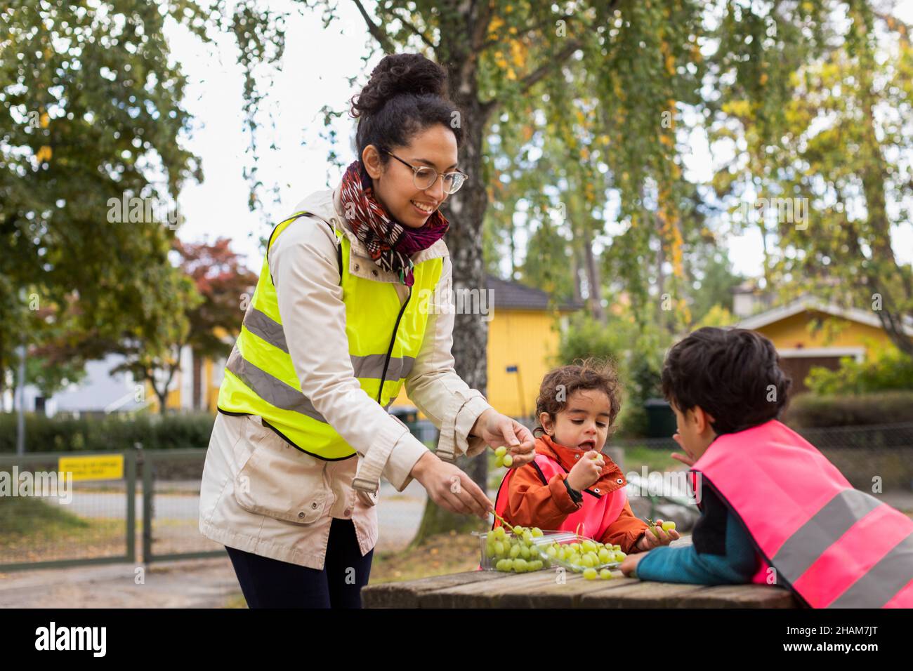 Preschool teacher and students eating grapes outdoors Stock Photo - Alamy