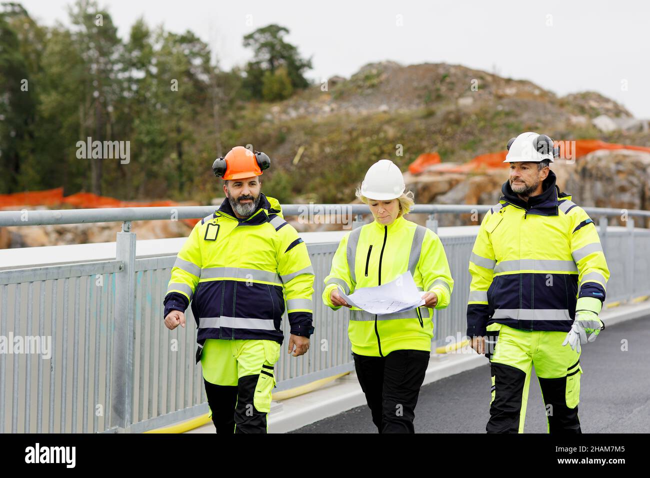 Engineers in reflective clothing walking on bridge Stock Photo - Alamy