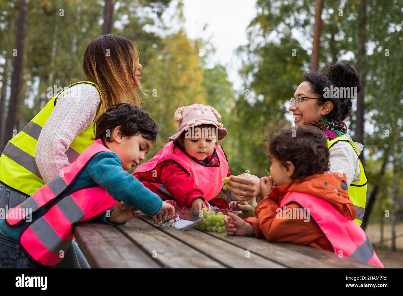 Preschool teachers and students eating grapes outdoors Stock Photo - Alamy