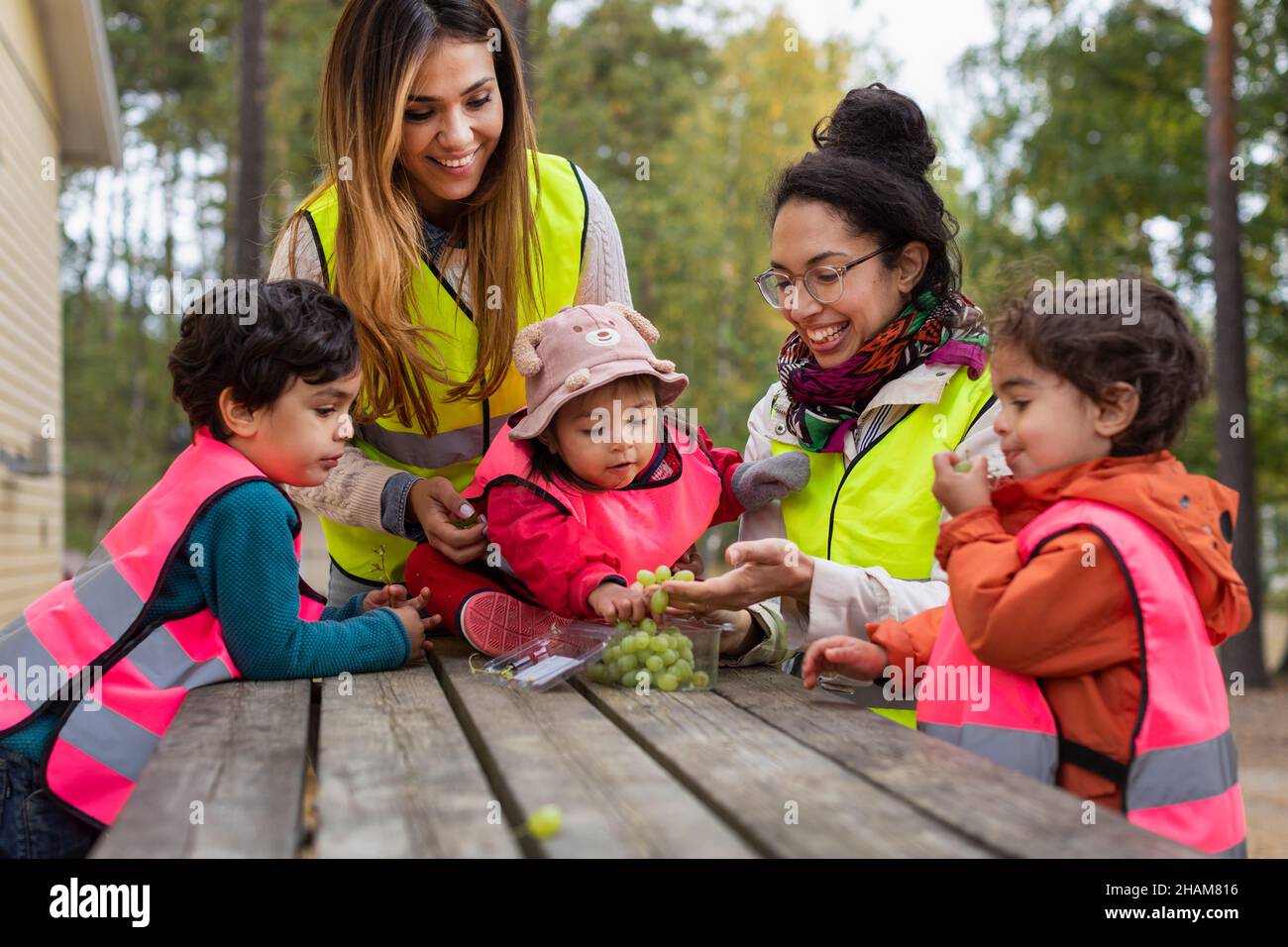 Preschool teachers and students eating grapes outdoors Stock Photo - Alamy