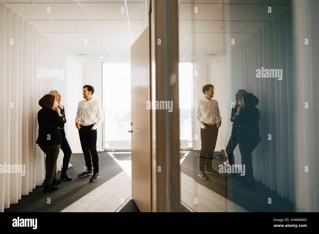 Coworkers talking at corridor Stock Photo - Alamy