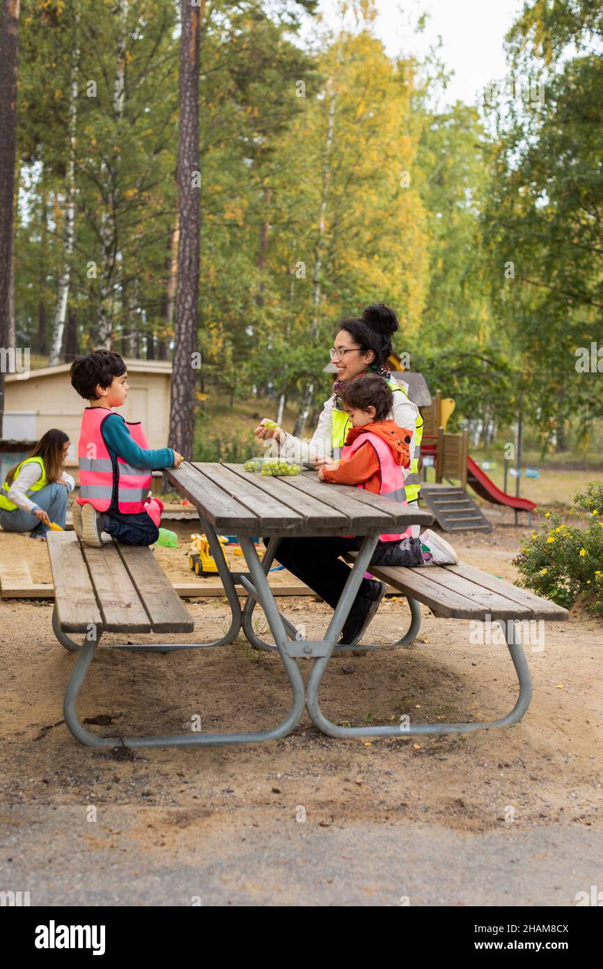 Preschool teacher and students eating grapes outdoors Stock Photo - Alamy