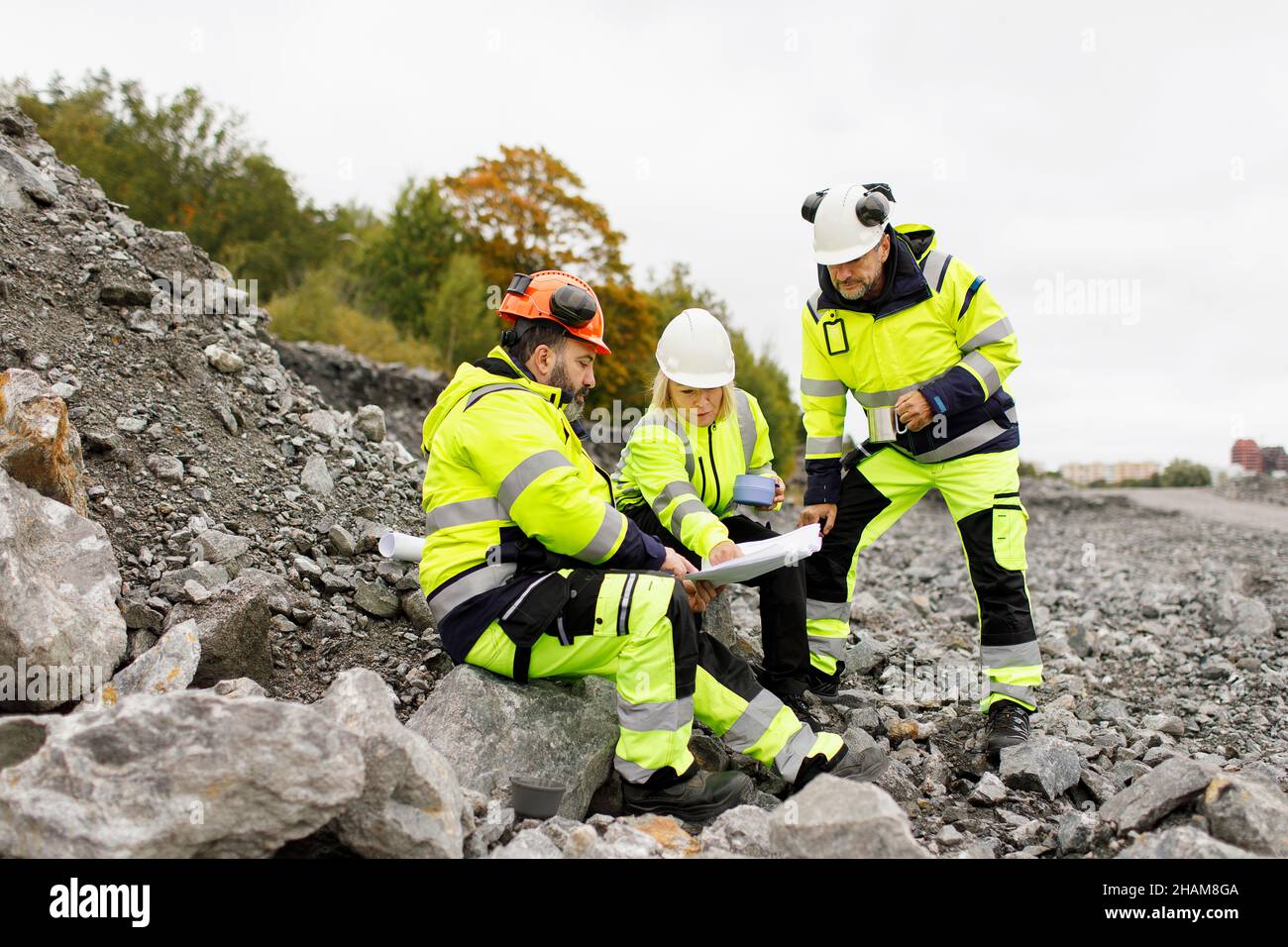 Engineers in reflective clothing looking at plans Stock Photo - Alamy