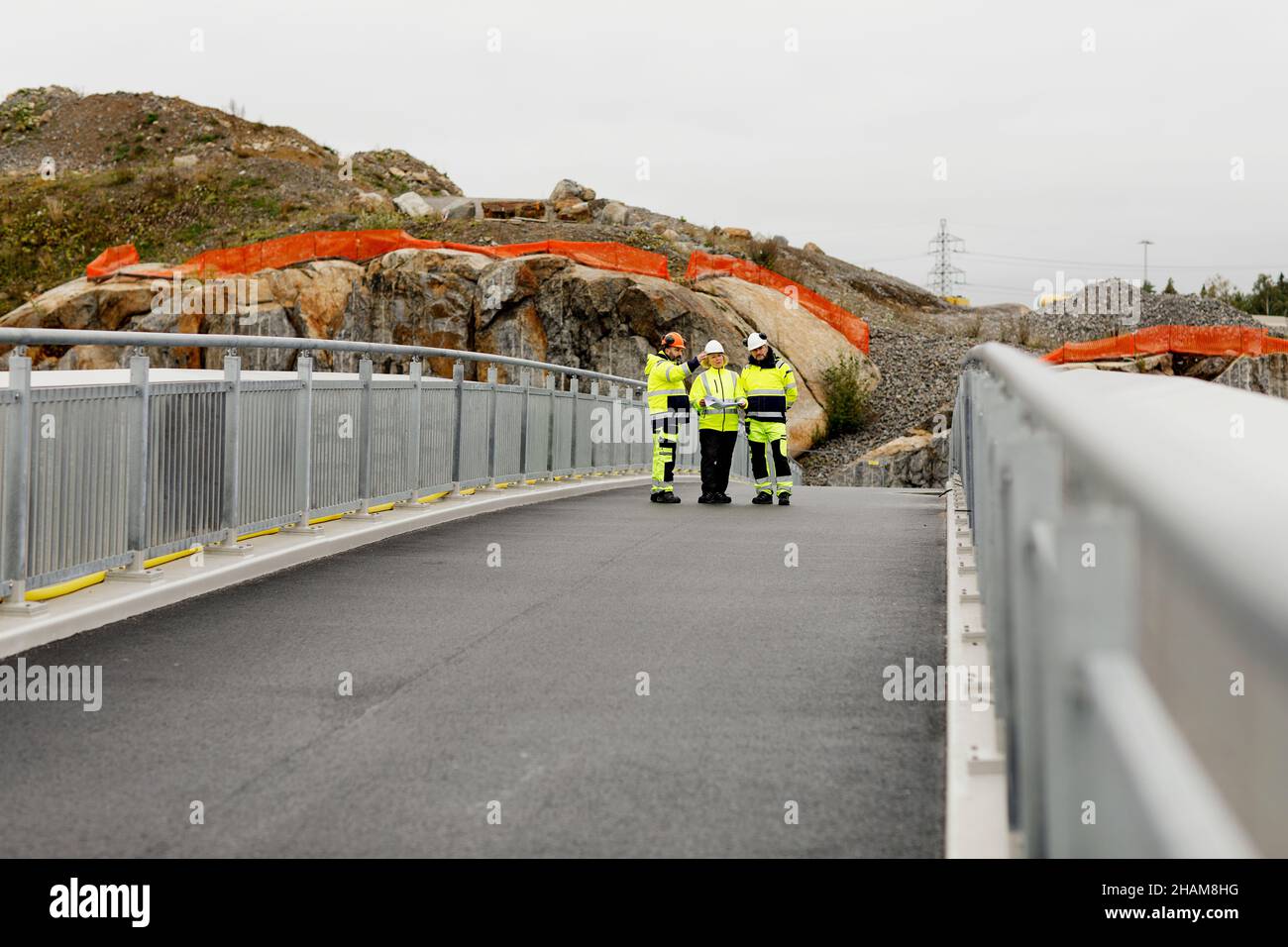 Engineers in reflective clothing walking on bridge Stock Photo - Alamy