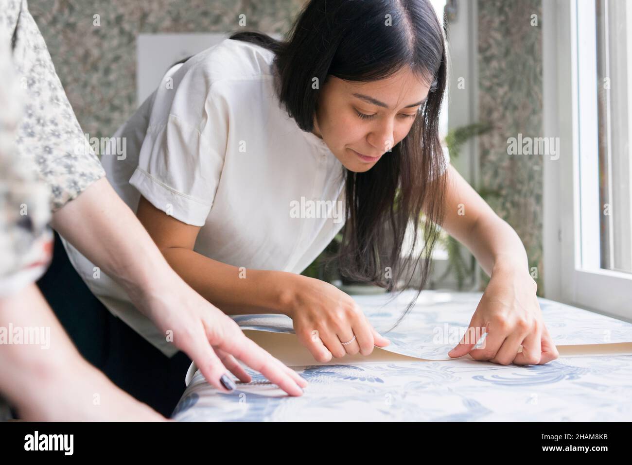 Woman checking pattern on wallpaper Stock Photo - Alamy