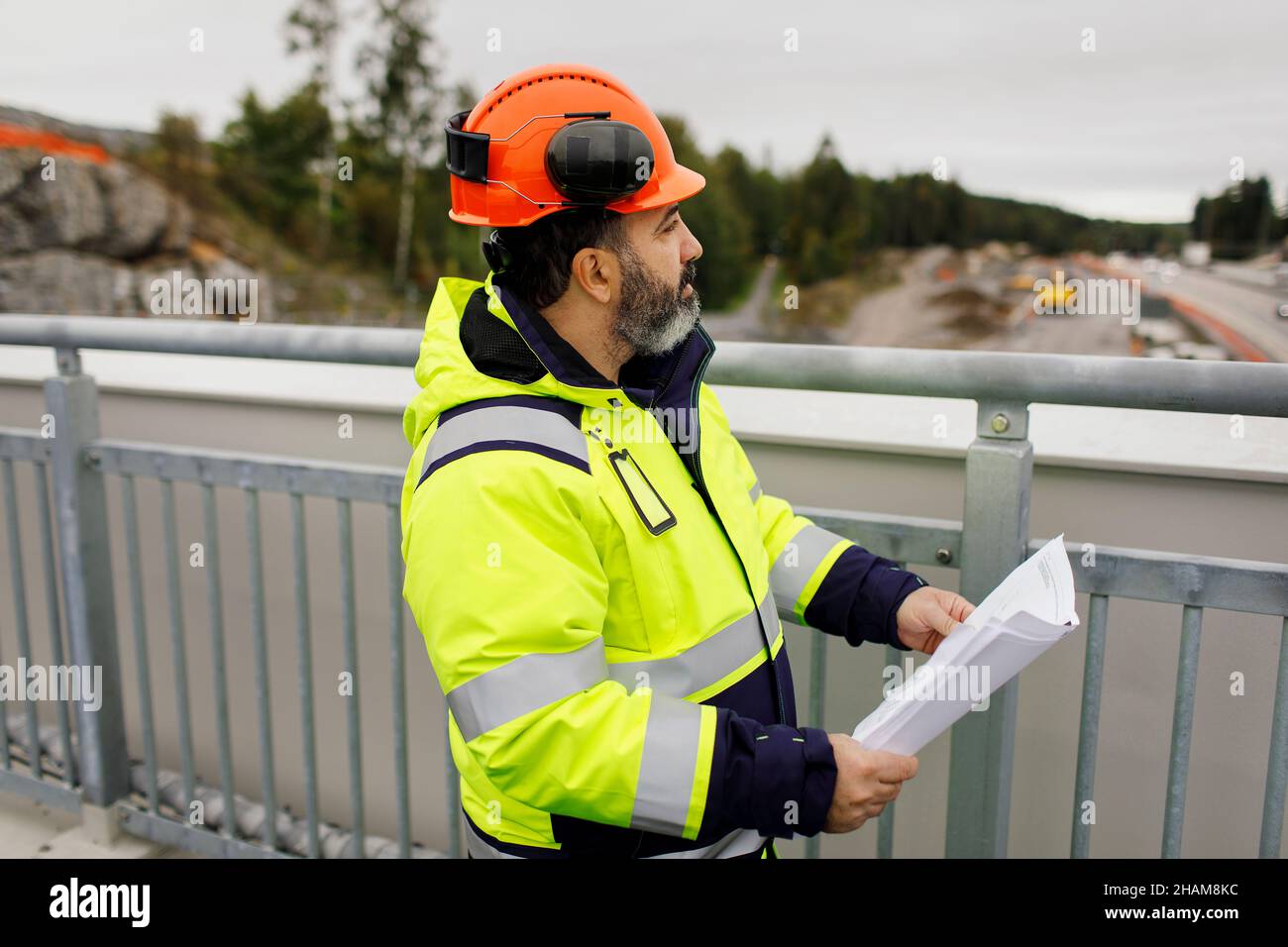 Male engineer in reflecting clothing holding blueprint Stock Photo - Alamy