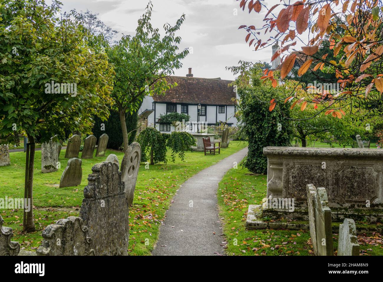 Path winding through an English churchyard, gravestones on either side ...