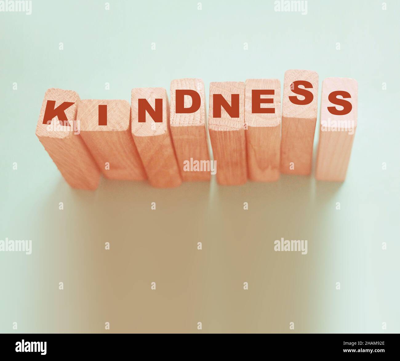KINDNESS word made with wooden building blocks on neon aquamarine ...
