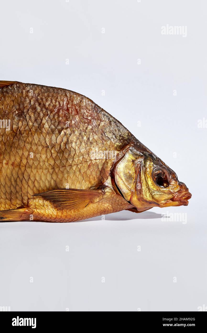 Closeup of head, fins and golden scales of cold-smoked bream on white ...