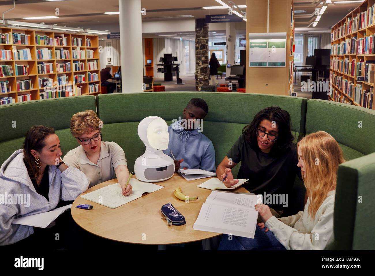 Friends sitting together in library Stock Photo - Alamy