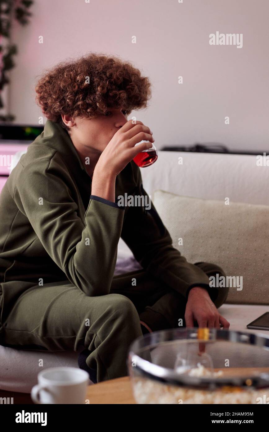 Boy sitting on sofa and drinking Stock Photo - Alamy