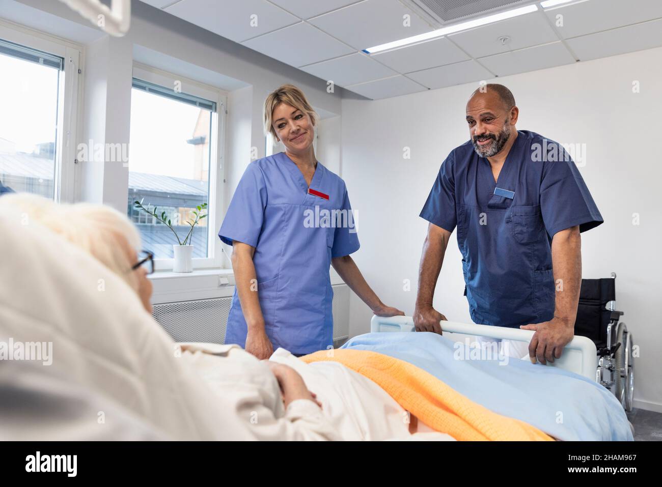 Nurses talking to patient on hospital bed Stock Photo - Alamy