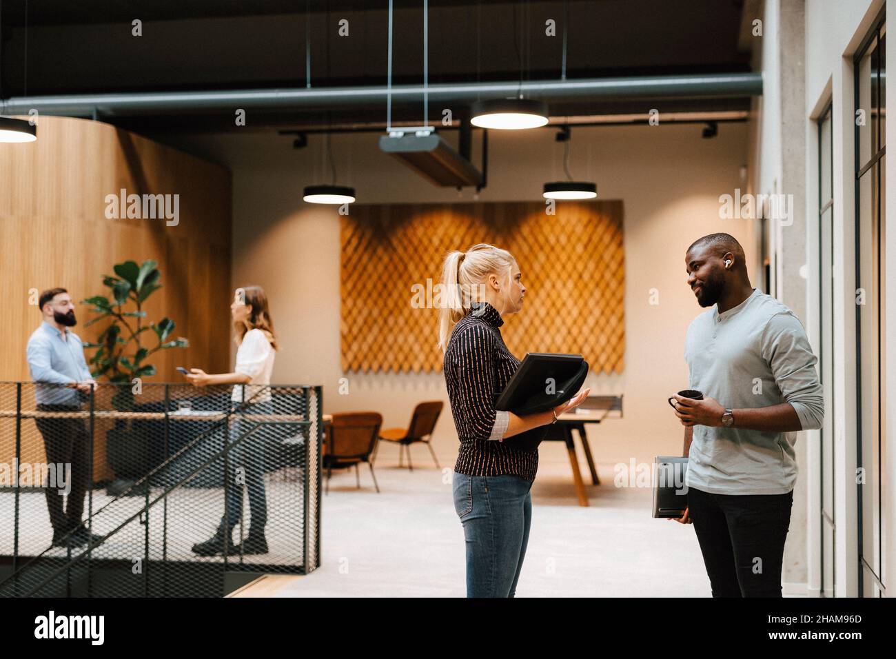 Coworkers talking at corridor Stock Photo - Alamy