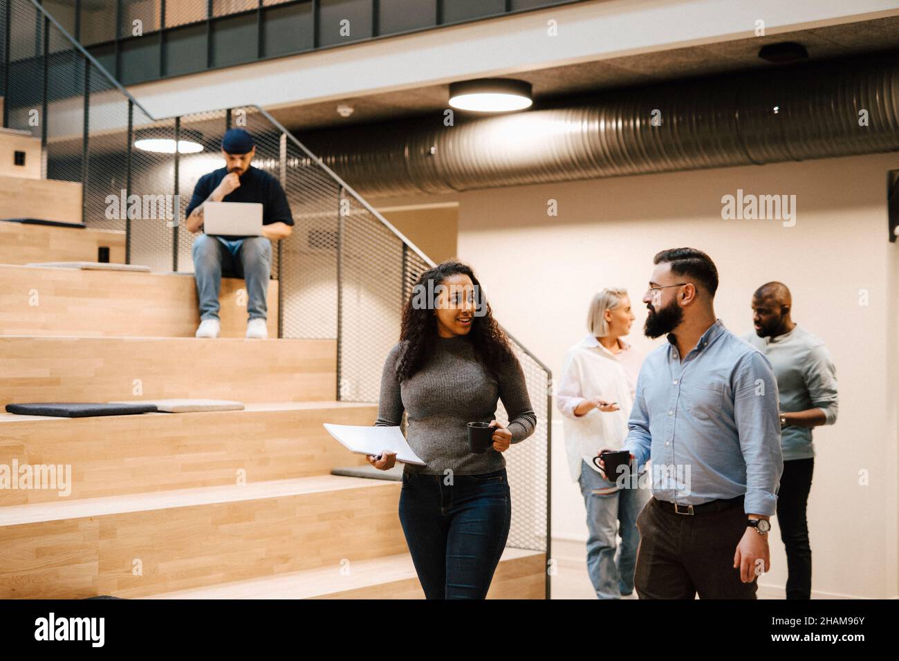 Coworkers talking at corridor Stock Photo - Alamy
