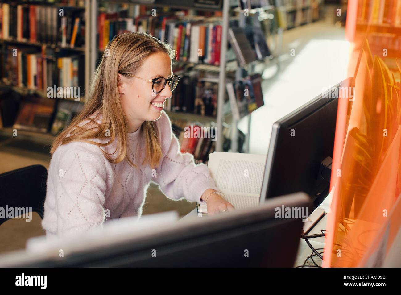 Woman using computer in library Stock Photo - Alamy