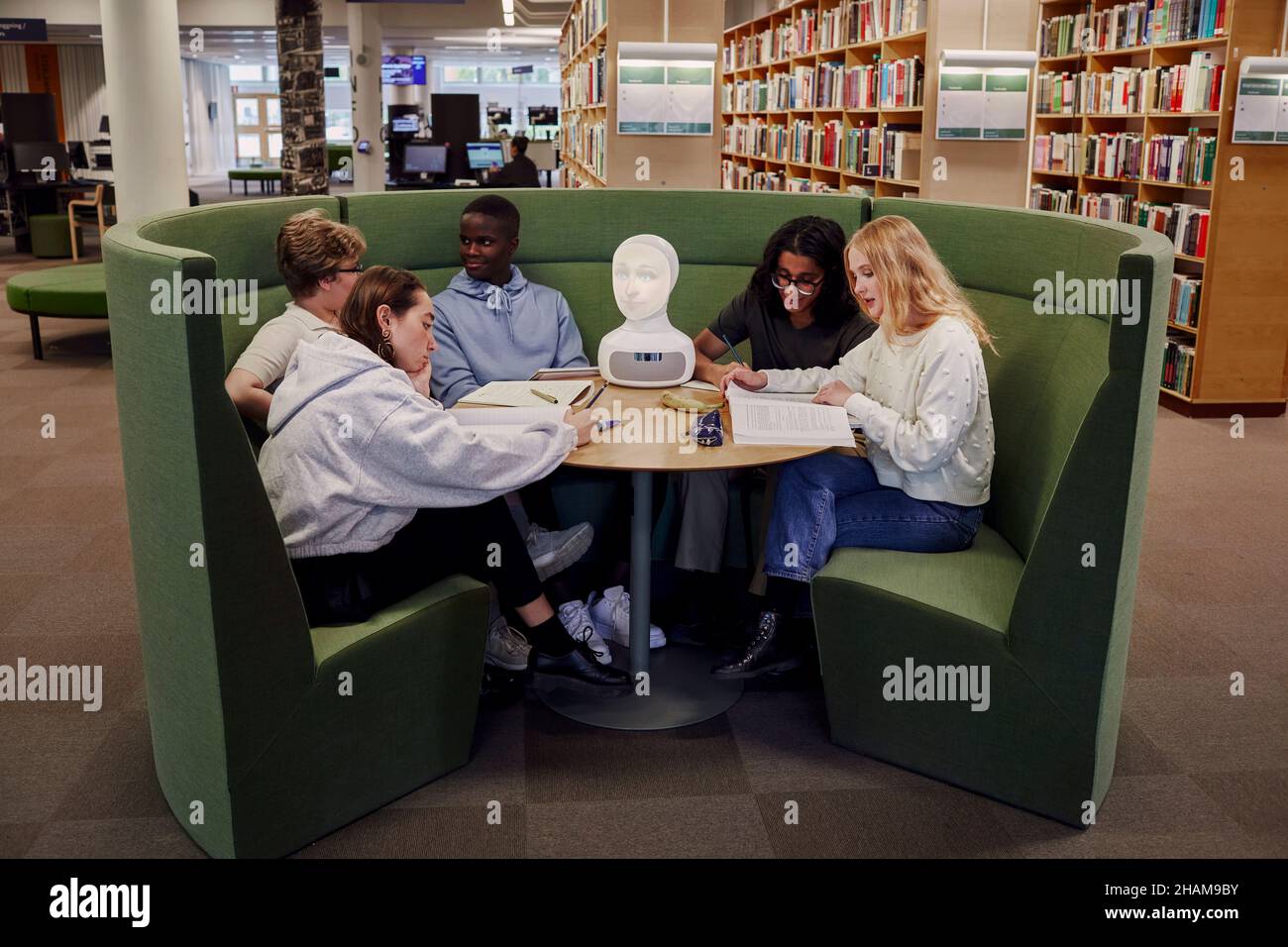 Friends sitting together in library Stock Photo - Alamy