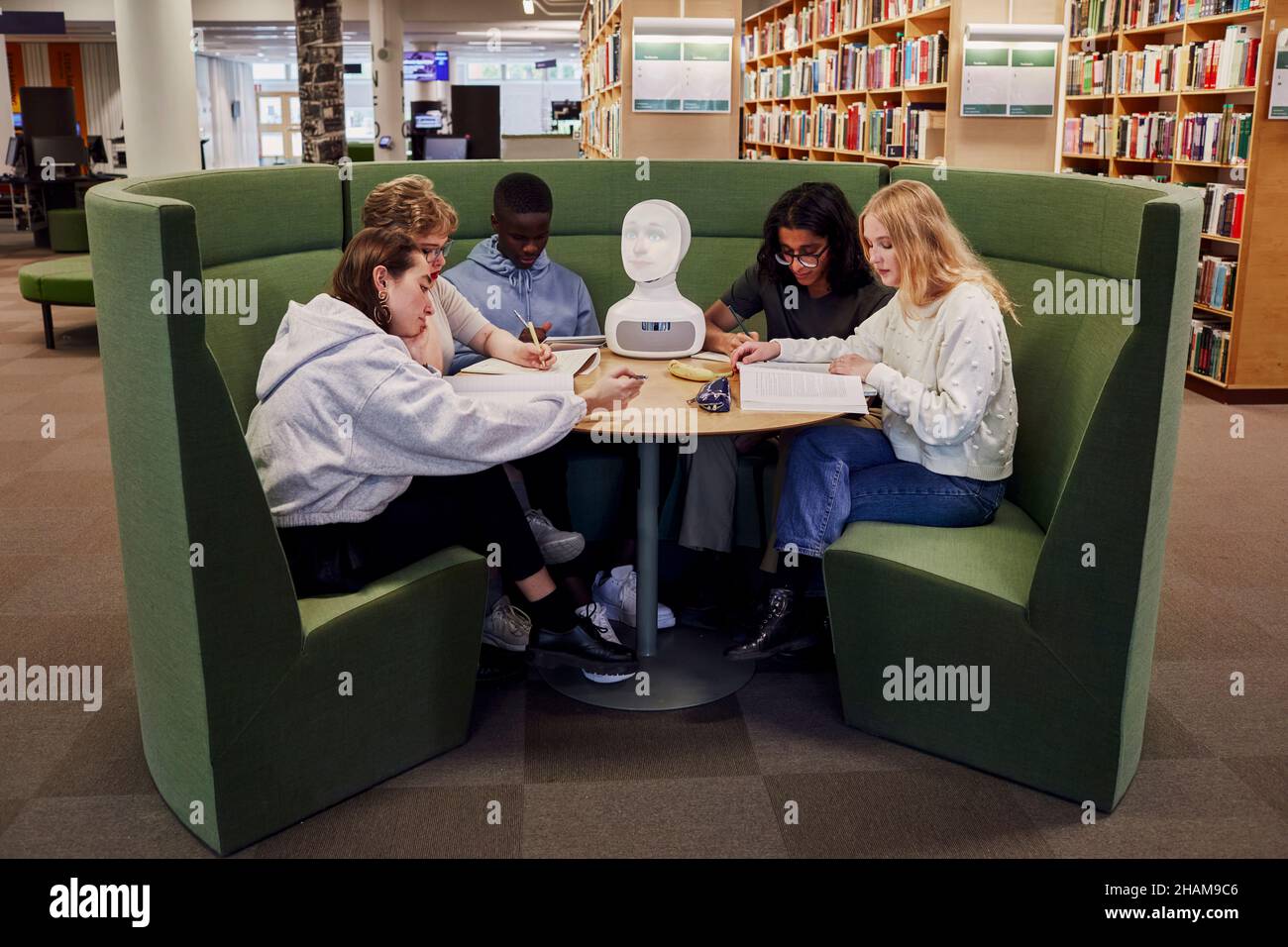 Friends sitting together in library Stock Photo - Alamy