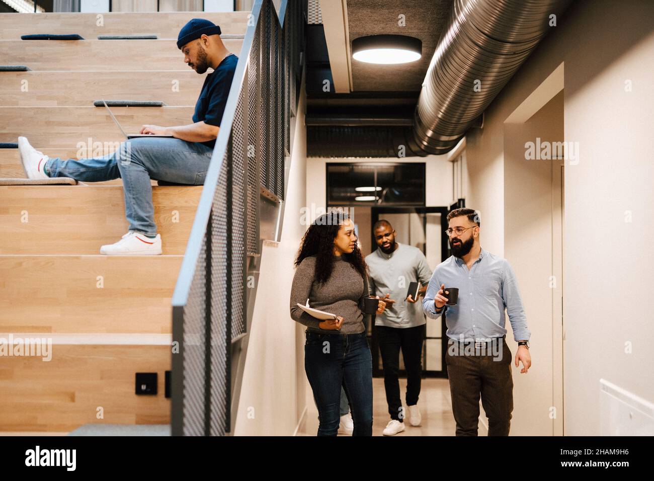 Coworkers talking at corridor Stock Photo - Alamy