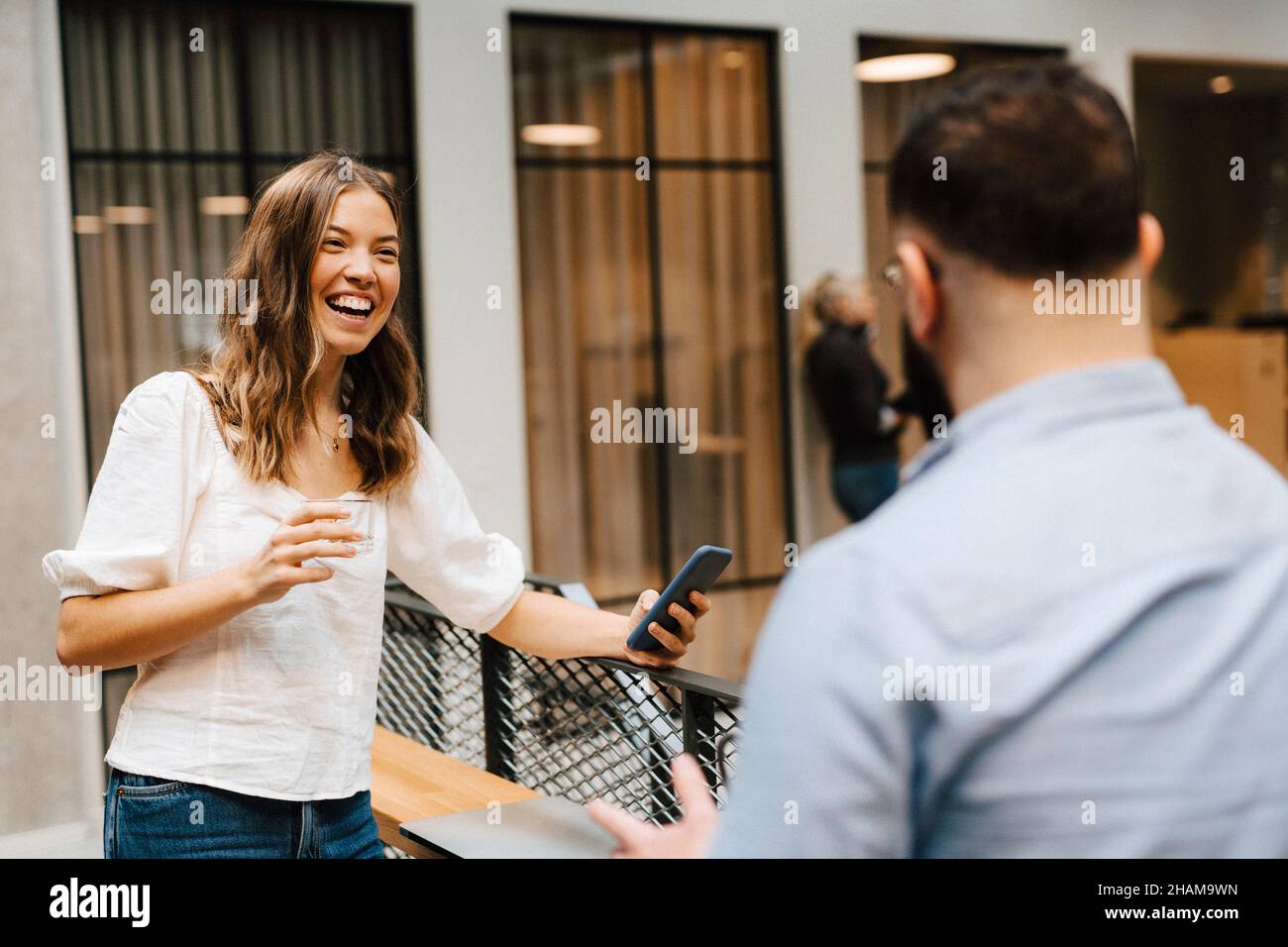 Coworkers talking at corridor Stock Photo - Alamy