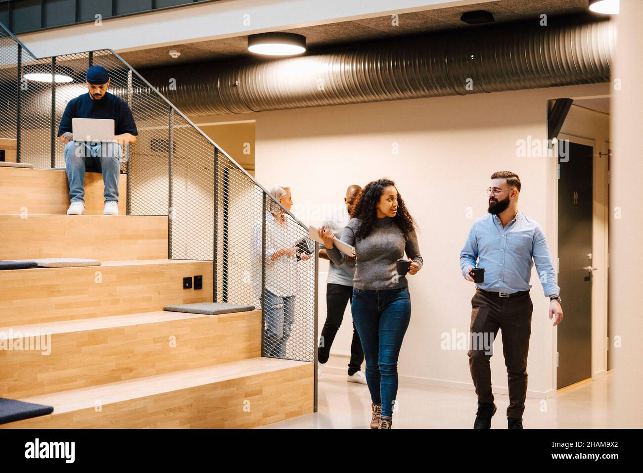 Coworkers talking at corridor Stock Photo - Alamy