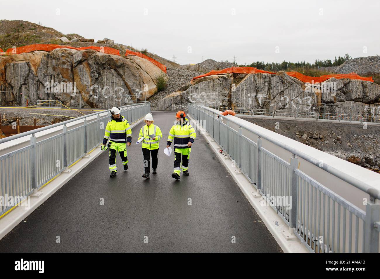 Engineers in reflective clothing walking on bridge Stock Photo - Alamy