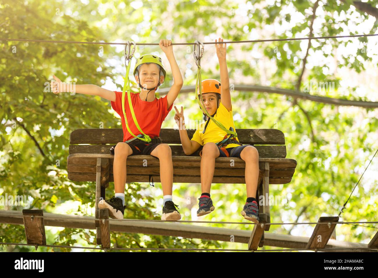 Child in forest adventure park. Kids climb on high rope trail. Agility ...