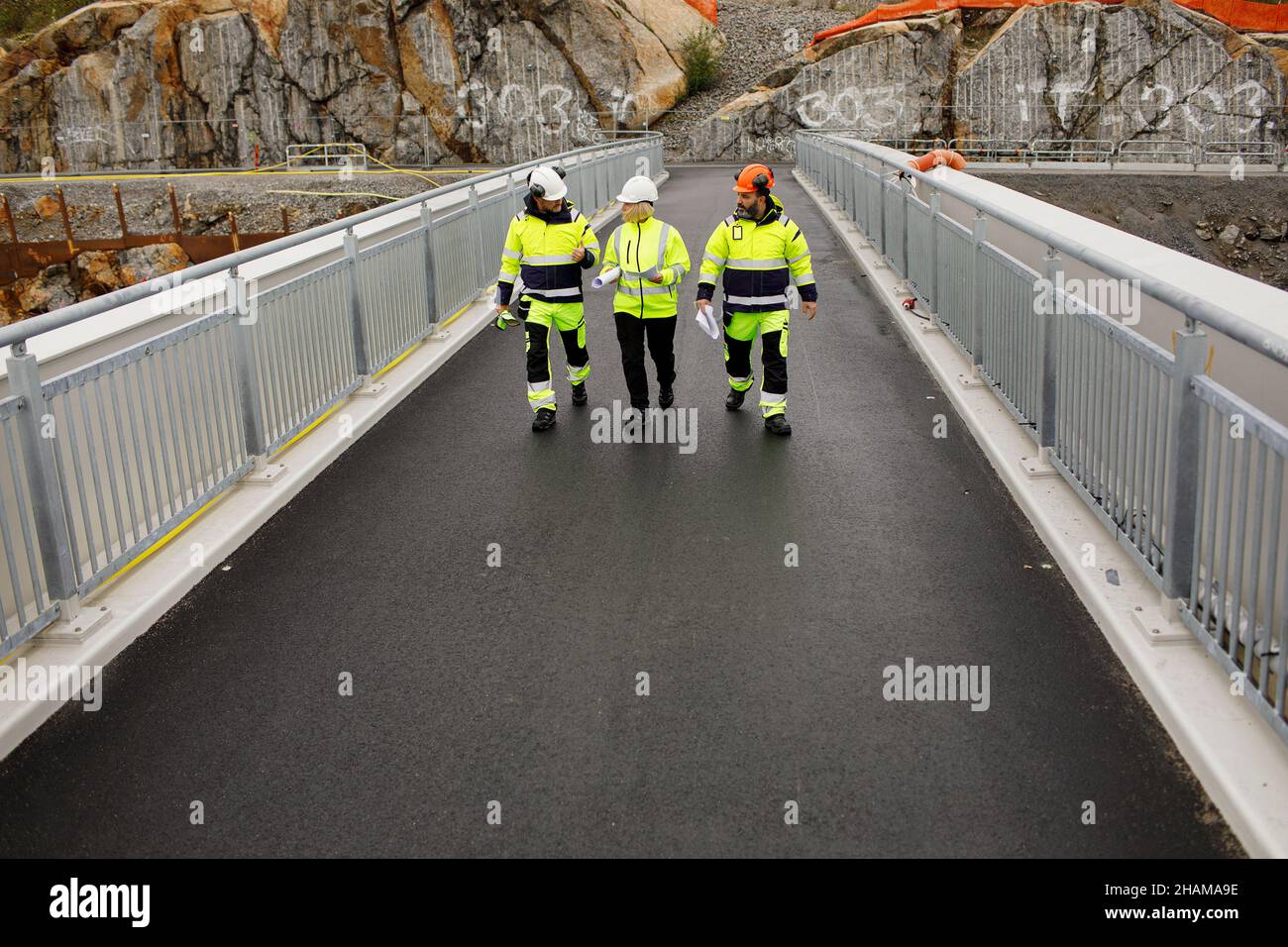 Engineers in reflective clothing walking on bridge Stock Photo - Alamy