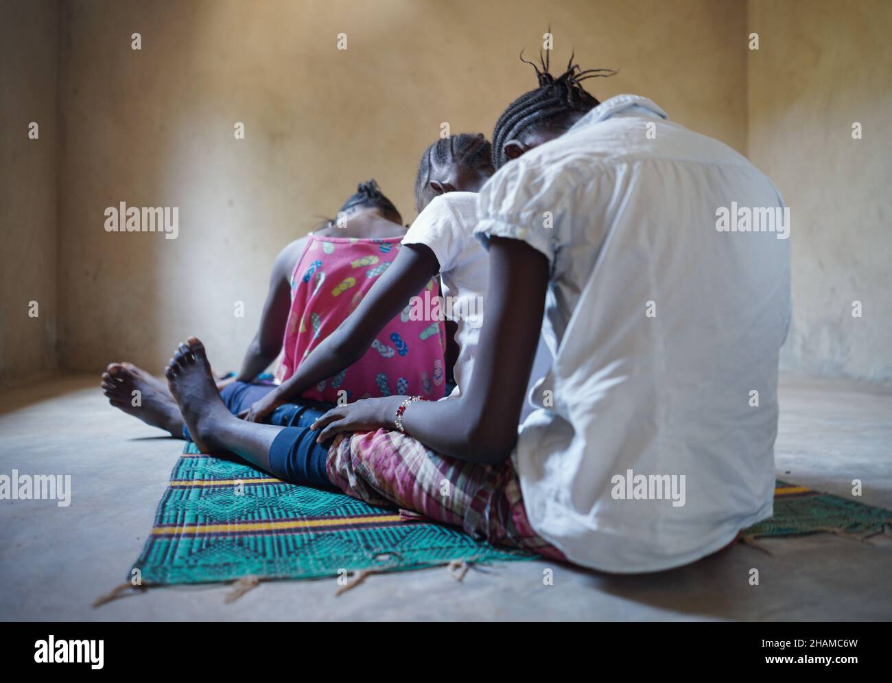 Back view group of african children sit on ground together perform ...