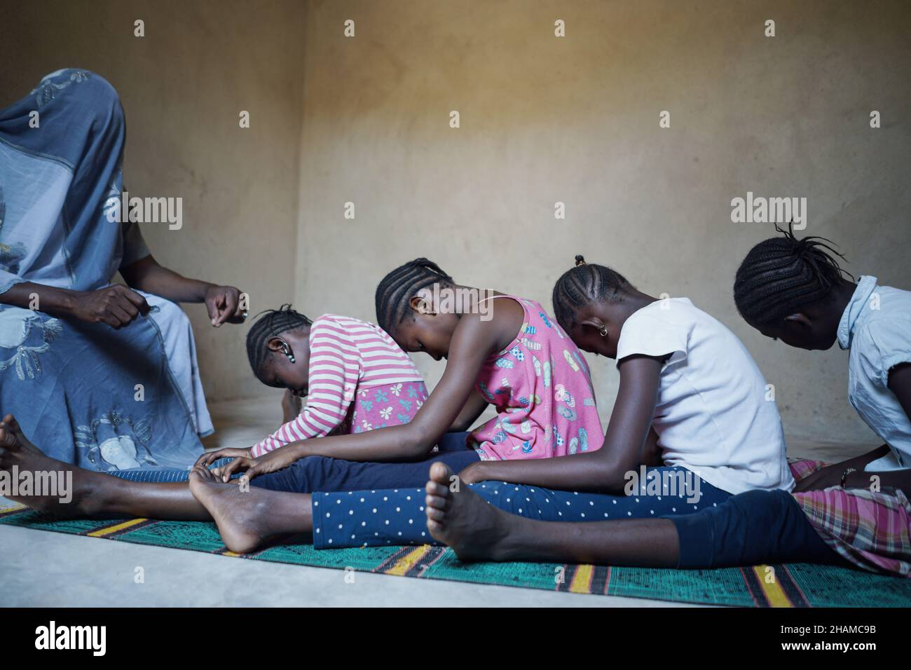 Group of young african children sit on ground together forming line in ...