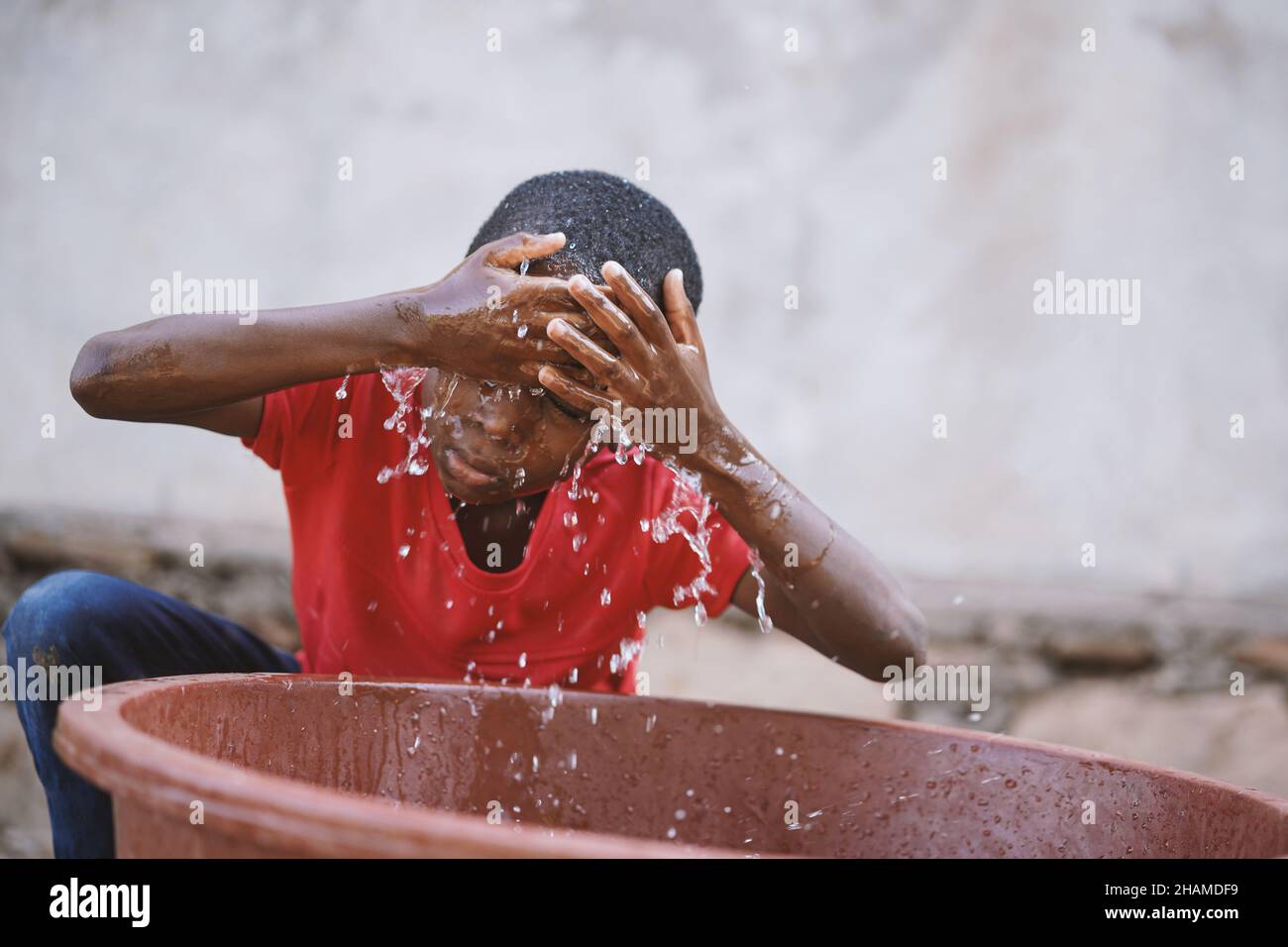Close up one young black african boy wash face with fresh clean water ...