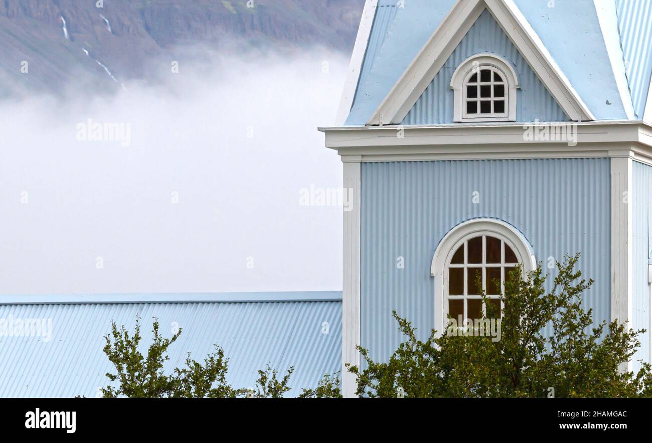 Wooden blue church in the mist, dwarfed by the mountain behind, Iceland ...