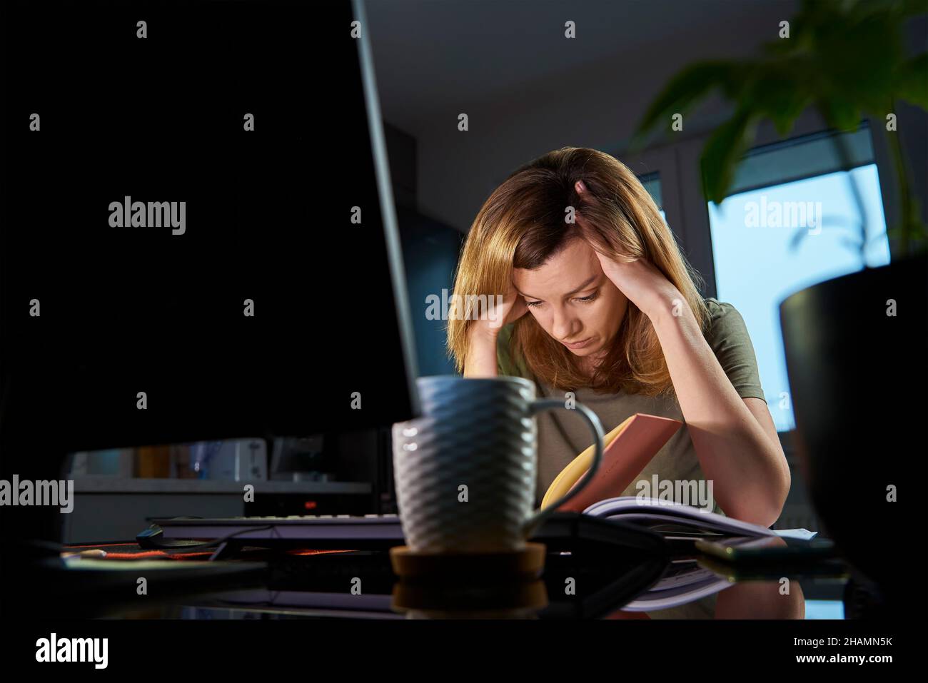 Thirty years old tired woman working late remotely at home office ...