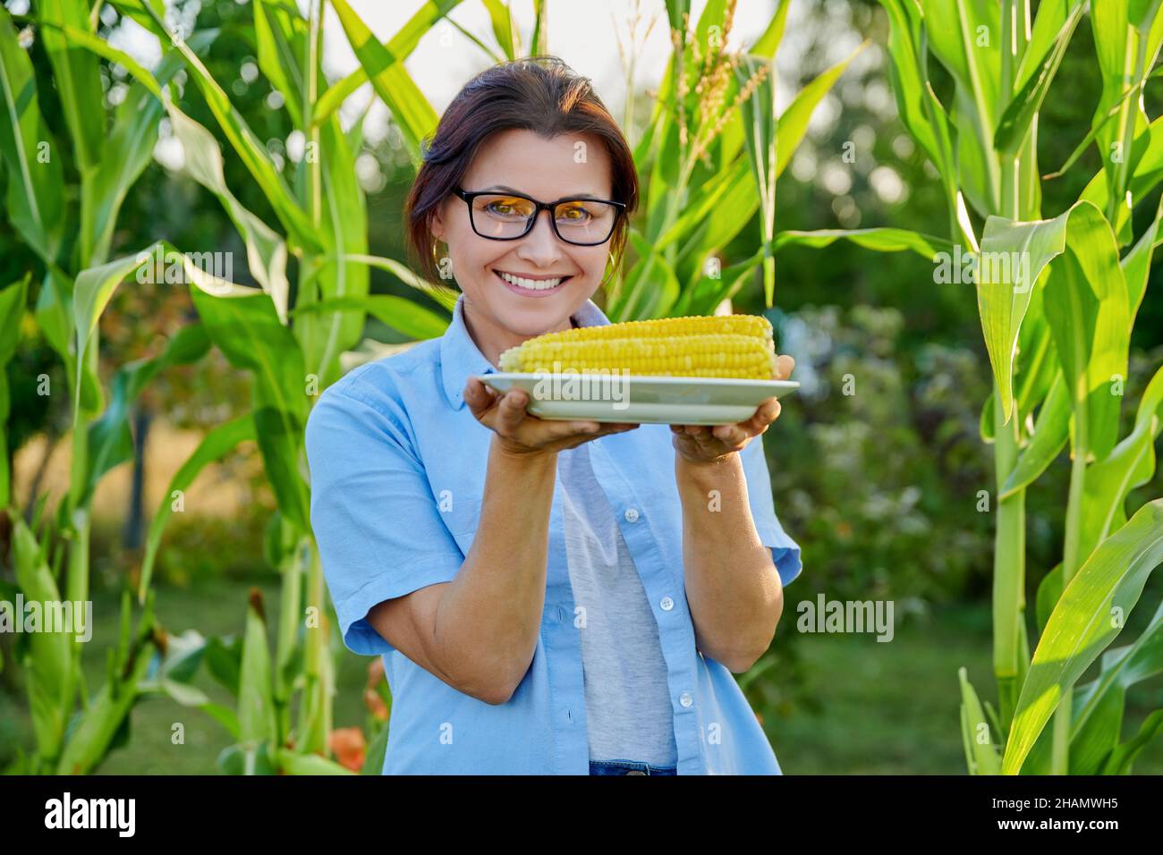 Middle-aged woman with boiled corn in plate Stock Photo - Alamy