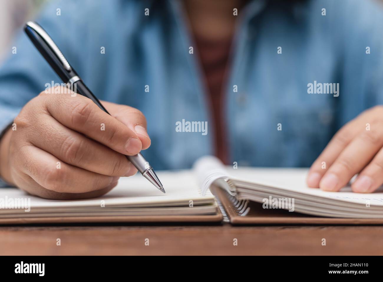 woman holding a pen sitting on a desk writing Stock Photo - Alamy