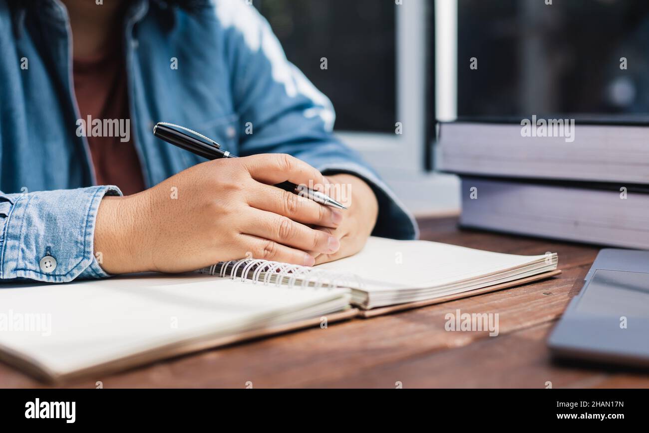 woman holding a pen sitting on a desk writing Stock Photo - Alamy